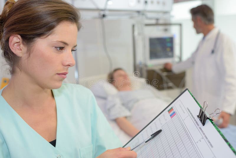 Nurse Looking at Chart on Clipboard Stock Photo - Image of hospital ...