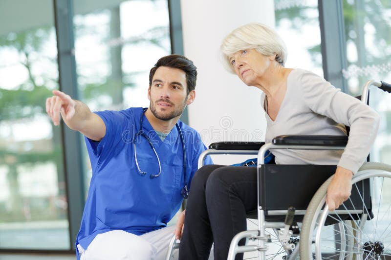 Nurse Pointing at Something with Senior Patient in Wheelchair Stock ...
