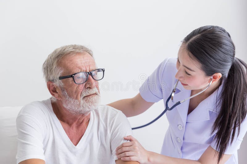 A Nurse with Stethoscope Visiting Senior Man and Checking His Heartbeat ...