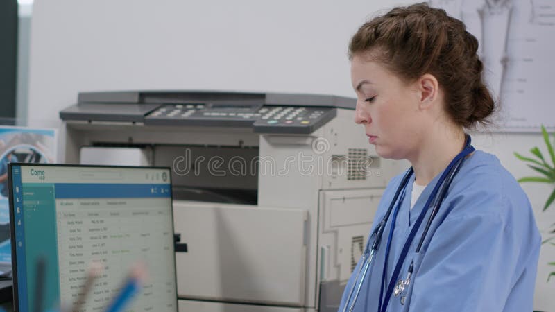 Nurse Using Computer with Appointments at Reception Desk Stock Video ...