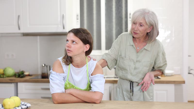 Sad Woman Ignoring Her Old Mother Standing In Background And Arguing