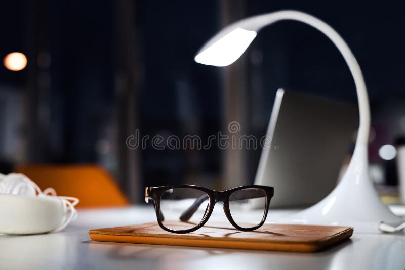 Office Desk at Night with Eyeglasses, Lamp and Tablet. Stock Image ...