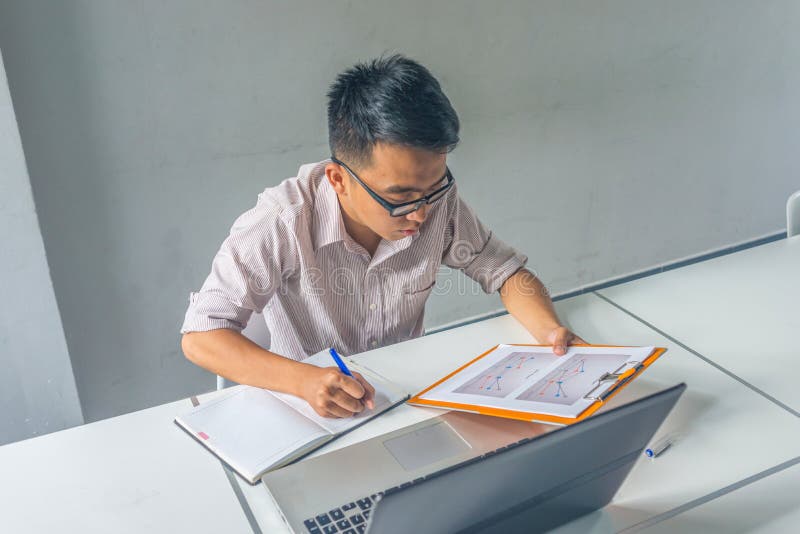 Office Employee Reading Financial Document and Writing Note Stock Photo ...