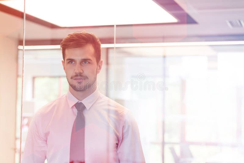 Thoughtful Young Professional Looking through Glass Window at Office ...