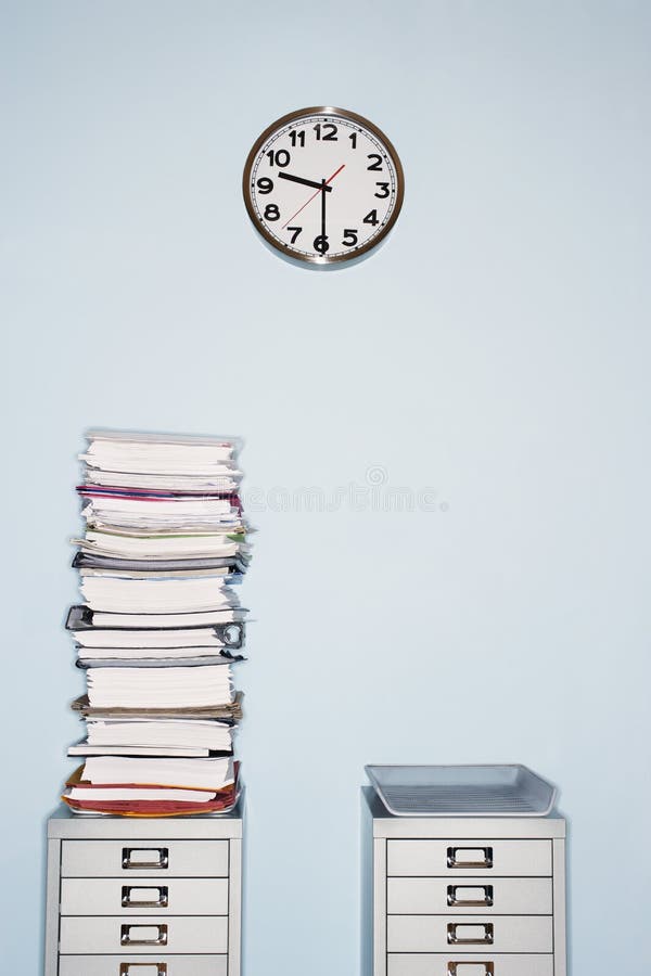 Office Wall with Clock Stack of Paperwork in Inbox on File Cabinet ...