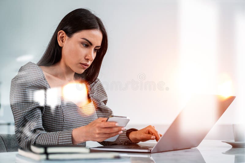 Businesswoman with Smartphone in Hands, Using Laptop in Office Room ...