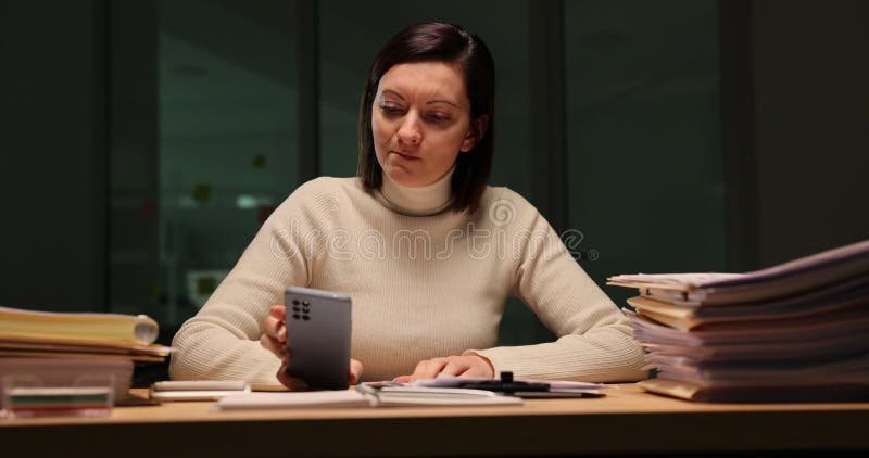 Office Worker Looking at Smartphone Overloaded with Paperwork and ...