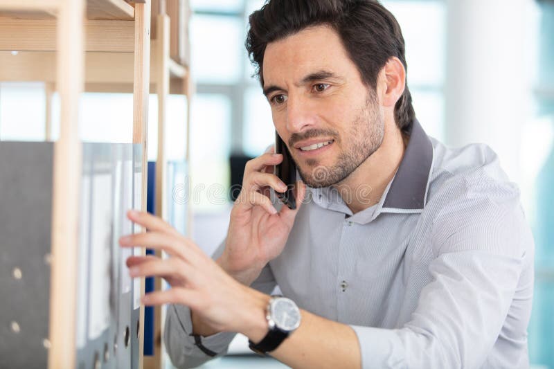 Office Worker Man Talking on Mobile Phone while Choosing File Stock ...