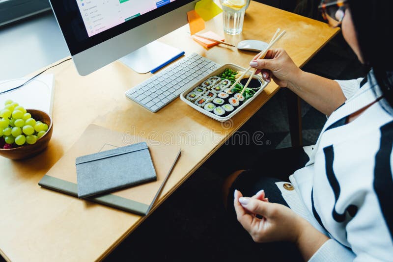 Office Worker Multitasks by Eating Sushi for Lunch and Concentrating on ...