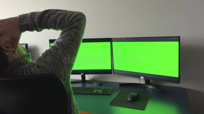 An Office Worker Sits in Front of Two Monitors with Chromakey Green ...