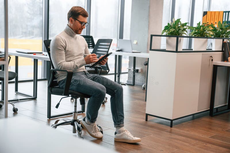 Office Worker is Sitting on the Chair in the and Using Tablet Stock ...