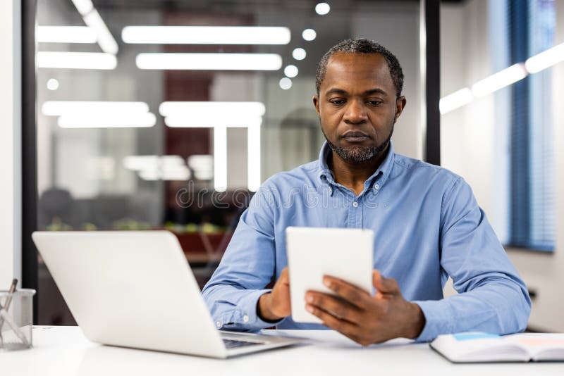 Professional Man Using Tablet for Work in Modern Office Setting with ...