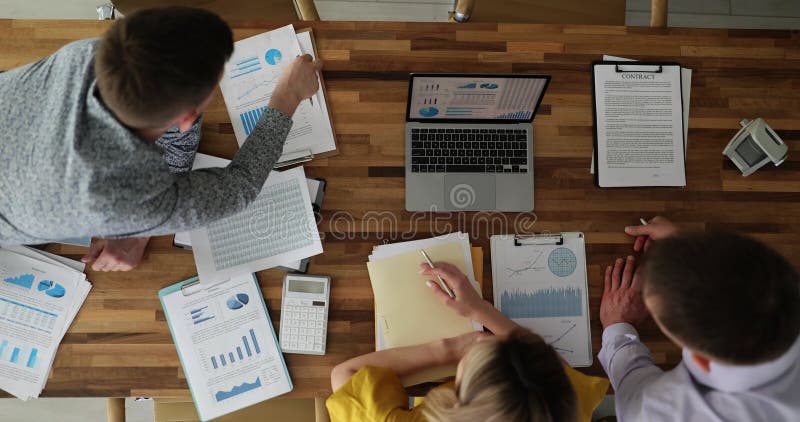Office Workers Examine Document with Charts Sitting at Table Stock ...
