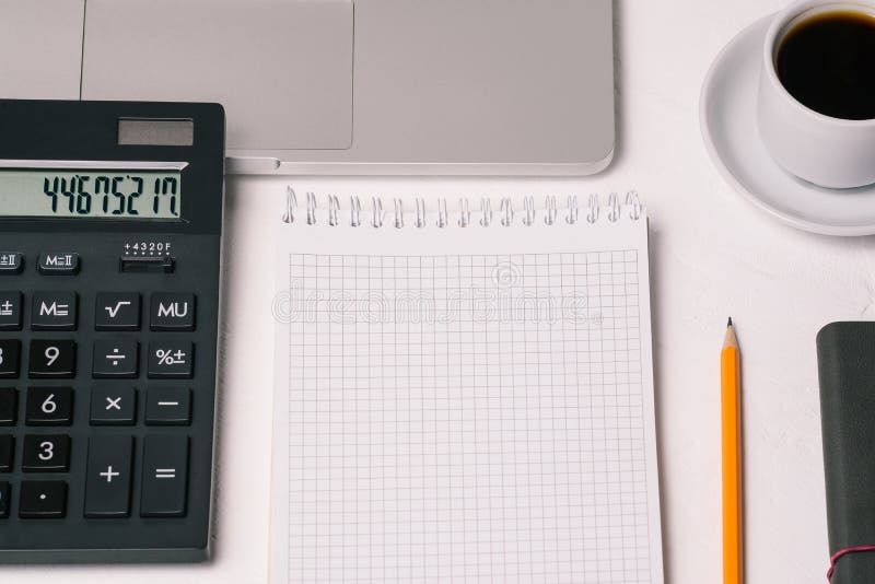 An Office Workplace with a Calculator, Laptop, Coffee Cup, and Notepad ...