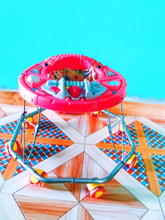 Old Baby Walker with Torn Seat on a Patterned and Colorful Tiled Floor ...