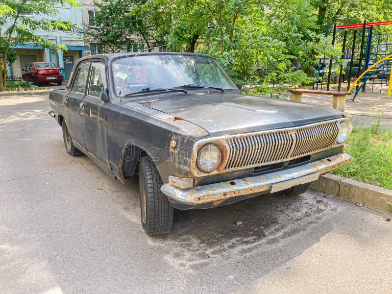 An Old, Battered Car is Parked on a Concrete Surface with Surrounding ...