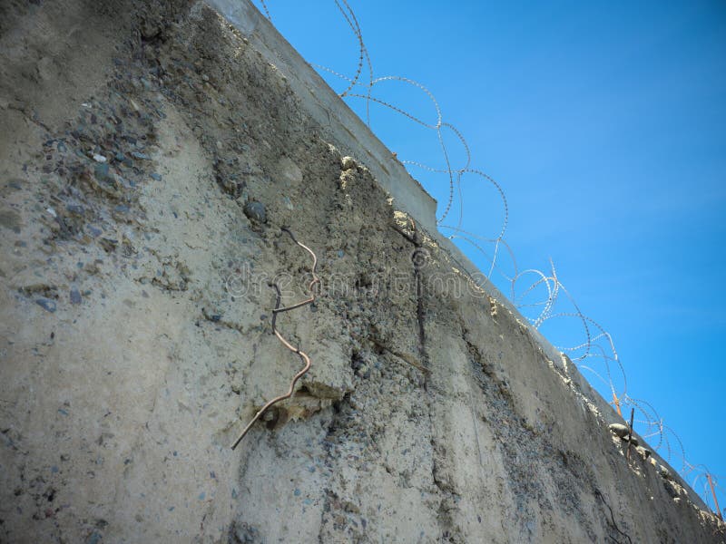 Old Decayed Concrete Wall with Barbwire on Top with Blue Sky Above ...