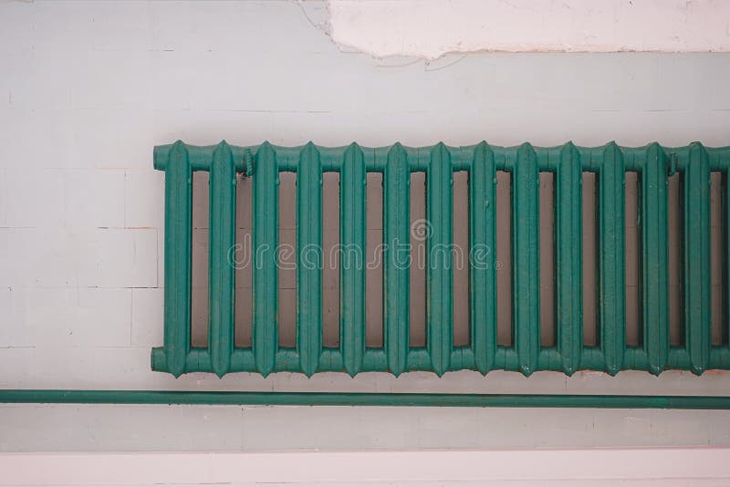Old-fashioned Green Heating Radiator on a Grey Tile Wall. Indoor ...