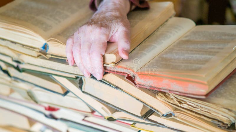 Old Female Hand is Lying on Stack of Book. Elderly Hand. Many Hardback ...