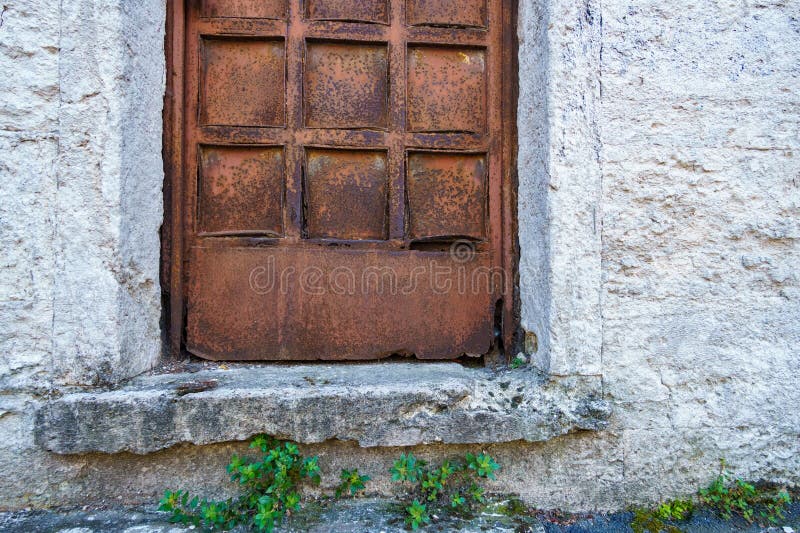 An Old Iron Door with Bars, Rusty, and a White Stone Wall Stock Image ...