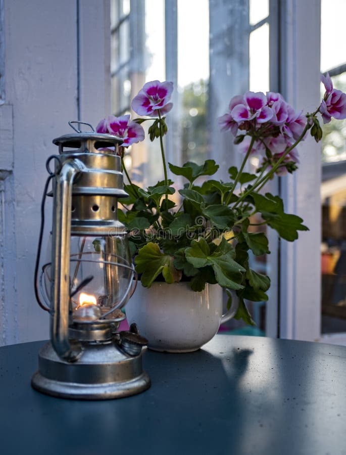Old Lantern Next To a Beautiful Pot with Flowers on a Table at a House ...