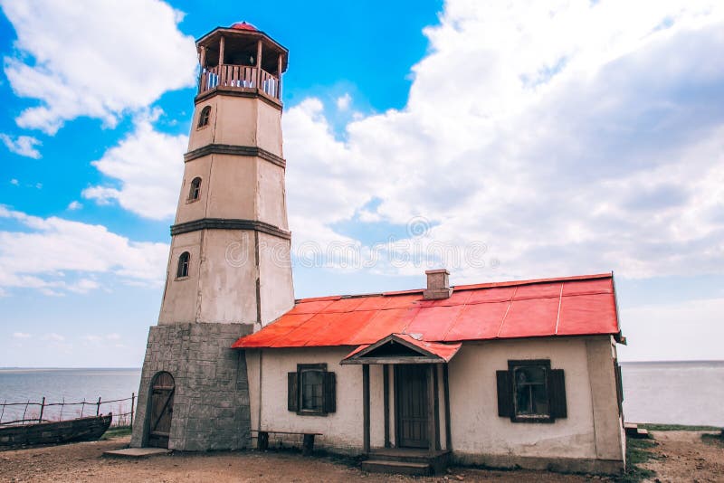 An Old Lighthouse and a House with a Red Roof on the Beach Stock Photo ...