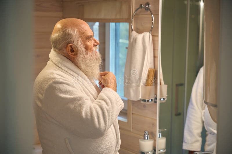 Old Man in Bathroom in Front of Mirror Combs His Beard Stock Image ...