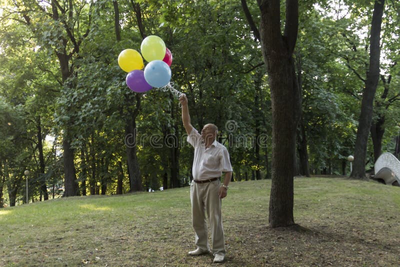 An Old Man is Playing in the Park with Bright, Balloons on His Birthday ...
