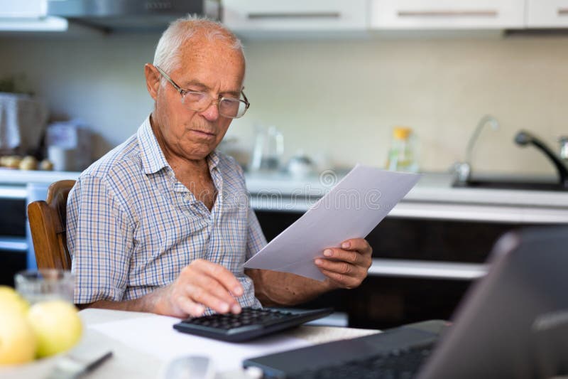 Old Man Sitting at Table and Counting with Calculator Stock Photo ...