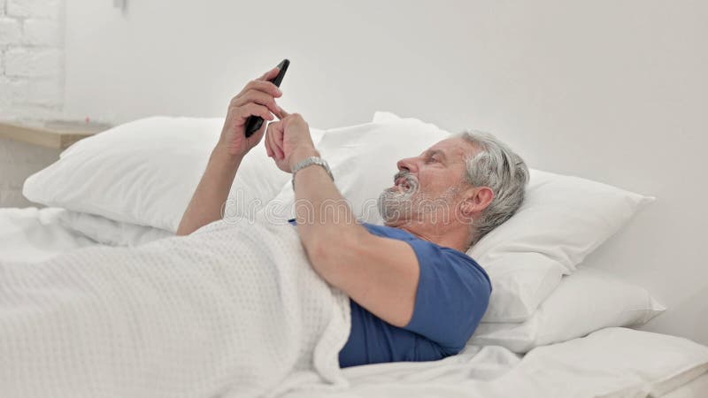 Senior Old Man Using Smartphone while Lying in Bed Stock Image - Image ...