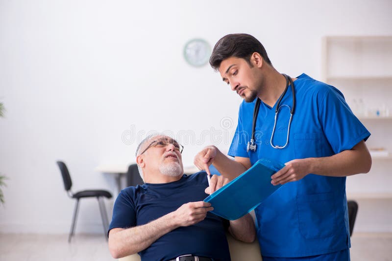 Old Man Visiting Young Male Doctor Stock Photo - Image of document ...