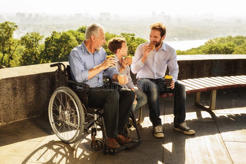 The Old Man In A Wheelchair His Son And His Grandson Eat In The Park
