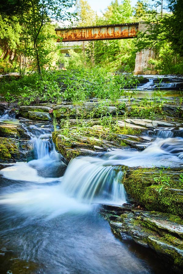 Old Rusted Bridge Above Beautiful Cascading Waterfalls Over Mossy Rocks ...