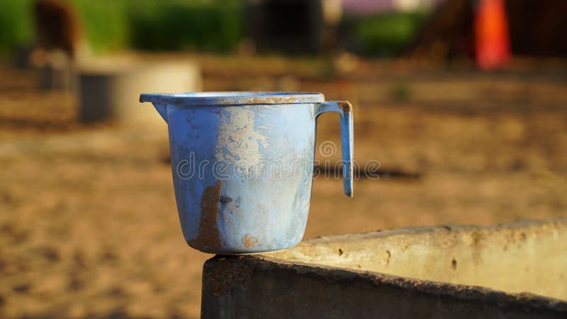 Old Rustic Plastic Watering Mug Holding on Rough Column. Blue Empty Mug ...