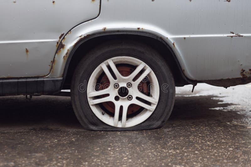 An Old Rusty Car with a Punctured Rear Wheel Stock Photo - Image of ...