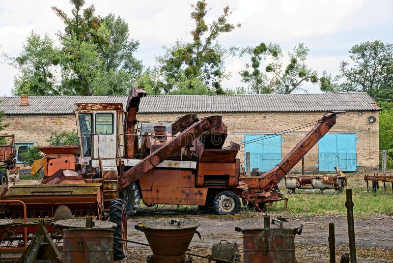 Old Rusty Combine and Scrap Metal in a Field Near a Brick Building ...