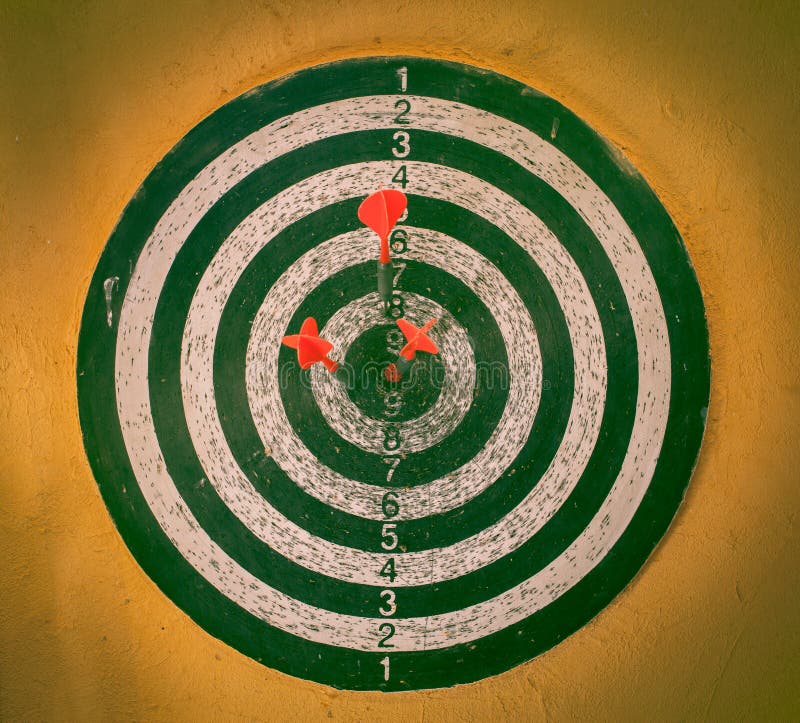 The Old Target with Darts in the Center on the Yellow Wall. Stock Photo ...