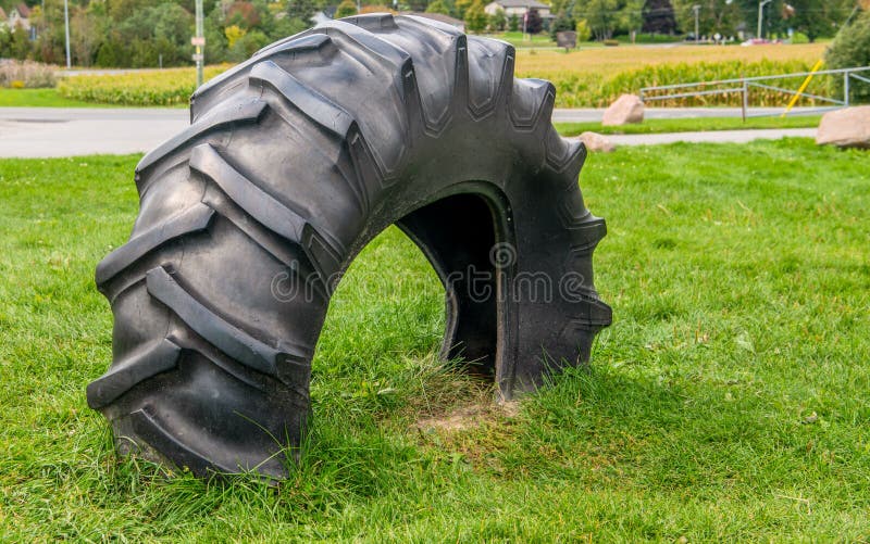 Old Tractor Tire in the Grass, Half in Ground Stock Photo - Image of ...