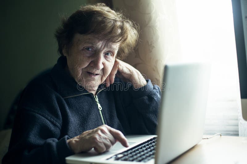 An Old Woman is Study Typing on a Laptop at Her Home. Stock Photo ...