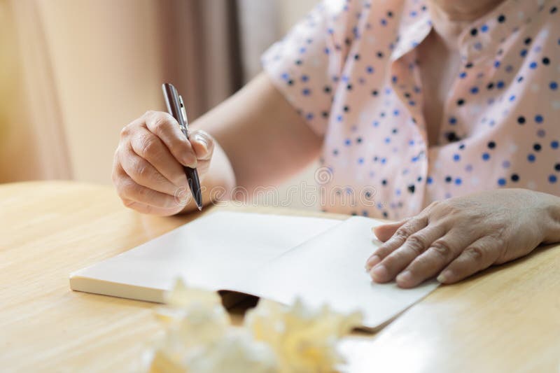 An Old Woman is Using a Pen To Write on a Book. Shot of a Senior Woman ...