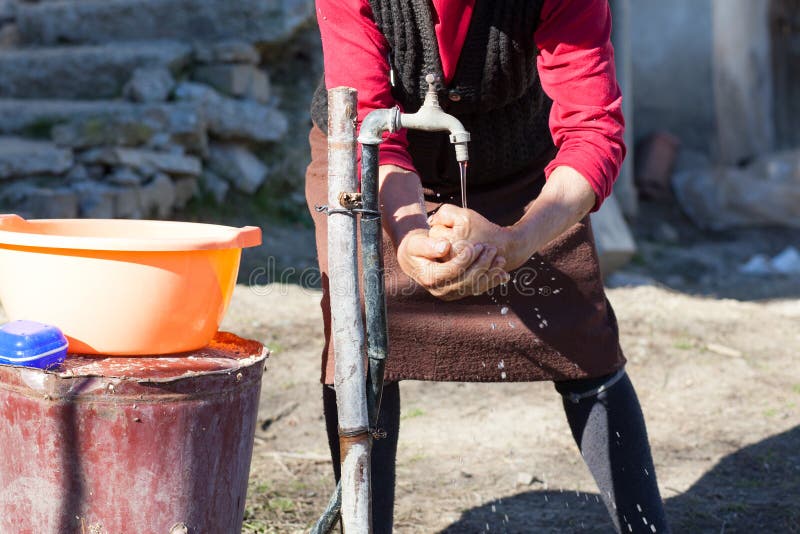 Old Woman Washing Hands in Rustic Courtyard Stock Photo - Image of ...