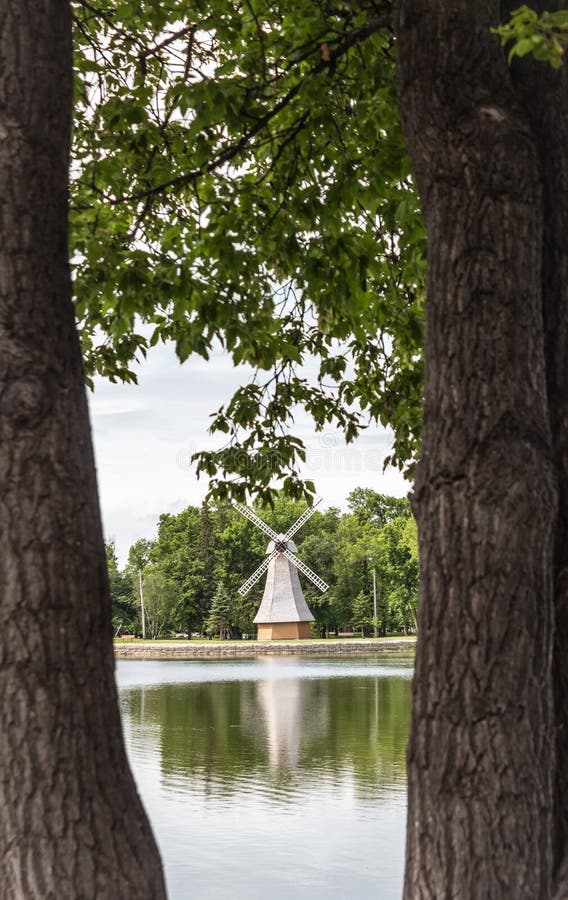 Old Wood Wind Mill by Lake Framed with Two Tree Trunks Stock Image ...