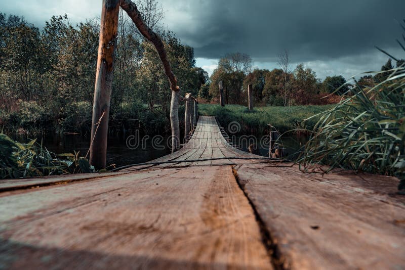 An Old Wooden Bridge Over a River that Opens into a Grassy Field Stock ...