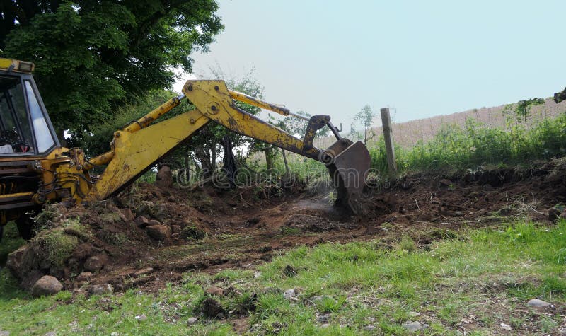Old Yellow Digger Digging Stones and Rocks on Farm Stock Photo - Image ...