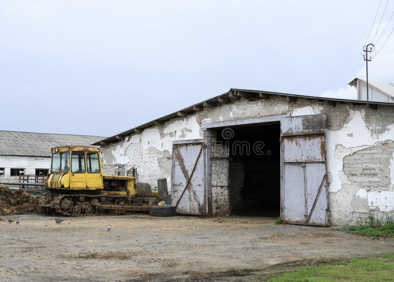 An Old Yellow Tractor in Front of a Farm Building Built Seventy Years ...