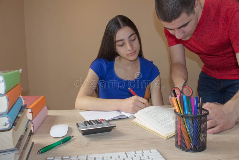 Older Brother Explaining Exercise Sister Working at Desk with Writing ...
