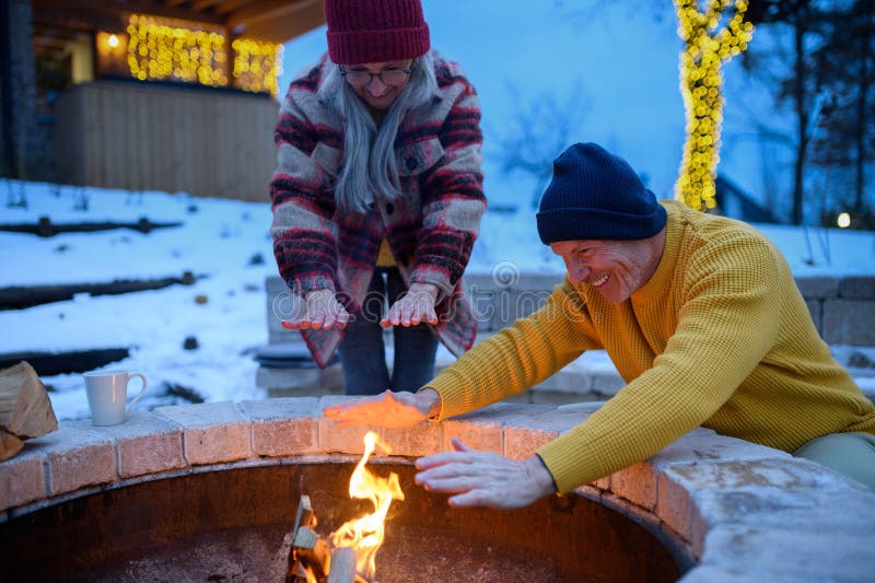 Older Couple Has Lit a Fire in Garden Fire Pit. Seniors Watching Flames ...