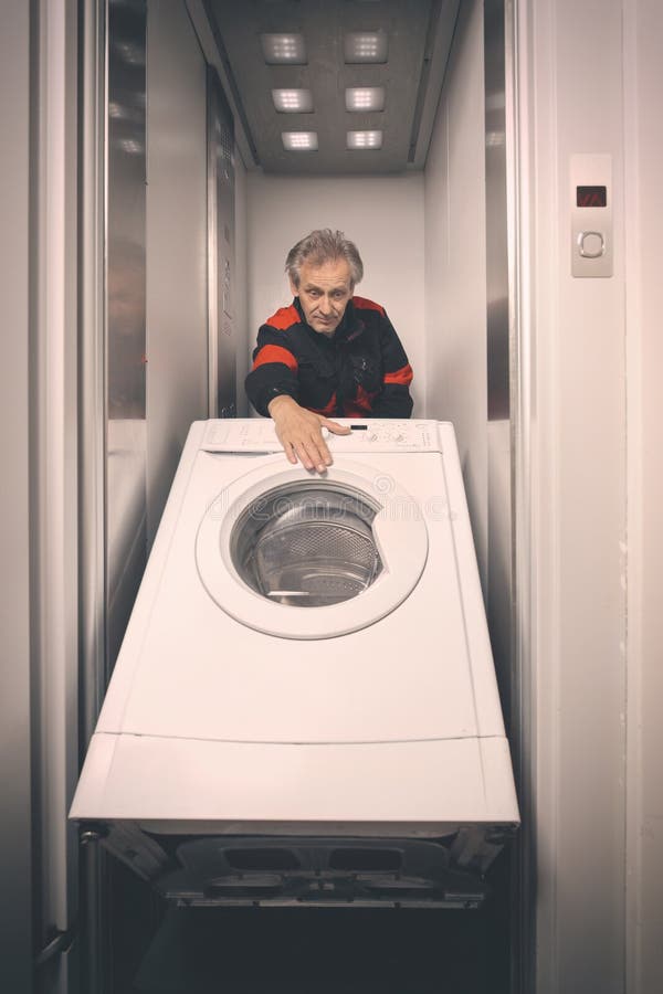 Older Worker Trasporting Wash Machine Appliace with Cart To Elevator ...