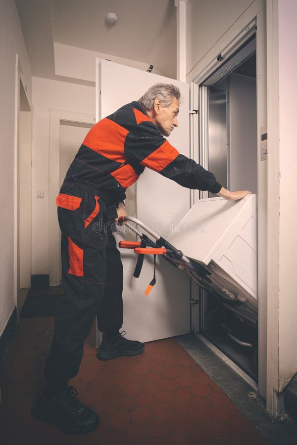 Older Worker Trasporting Wash Machine Appliace with Cart To Elevator ...
