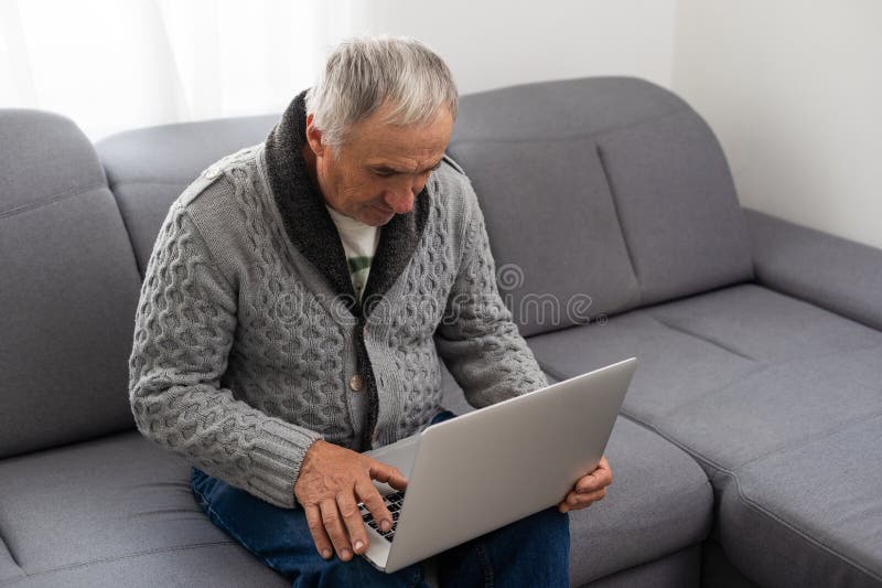 Older Man Sitting on Sofa, Smiling at Computer Screen at Home Stock ...